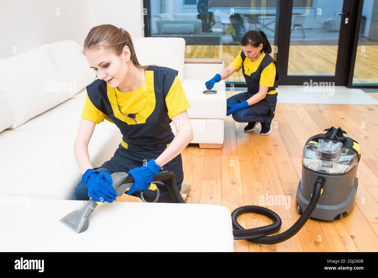 professional cleaning service. Two women in working uniform, in aprons ...