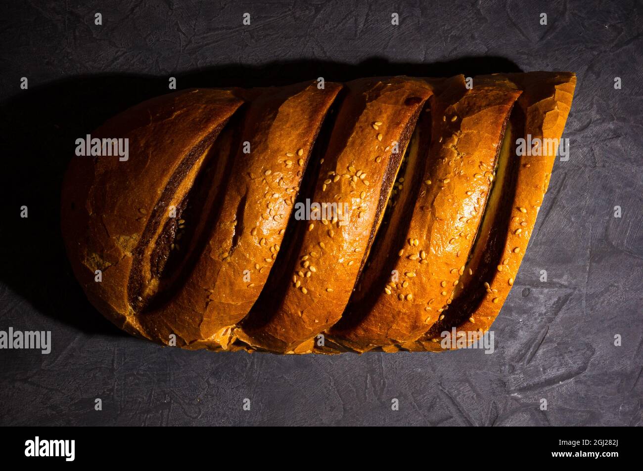 Unusual two-color fresh loaf of bread on a black background, photo in a ...