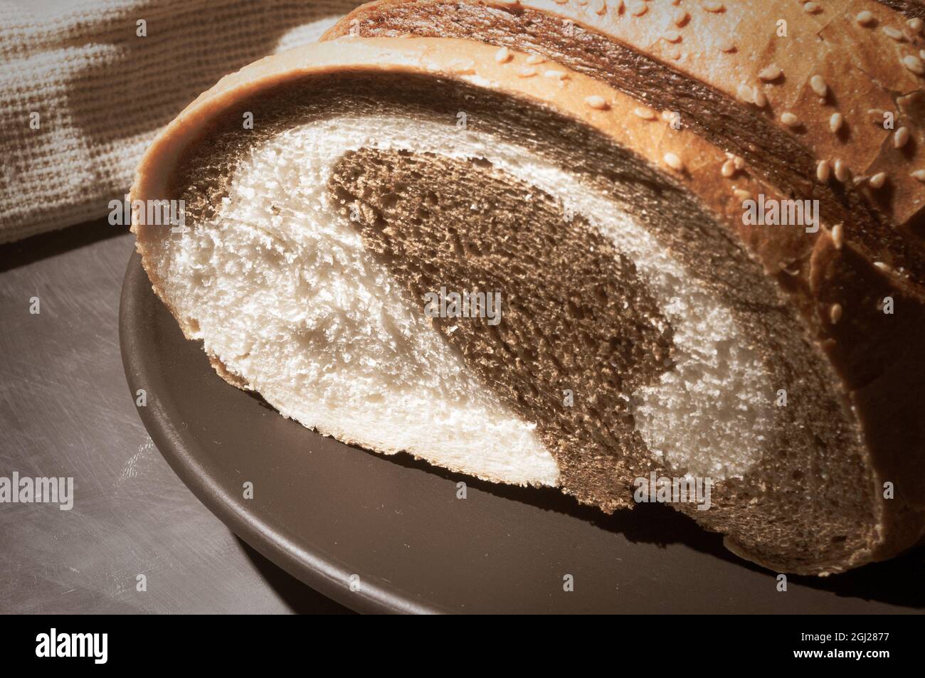 Unusual two-color fresh loaf of bread in a ceramic plate and a woven ...