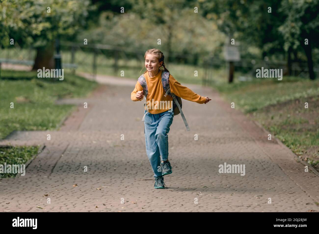 Pretty school girl with backpack running in the park after lessons ...