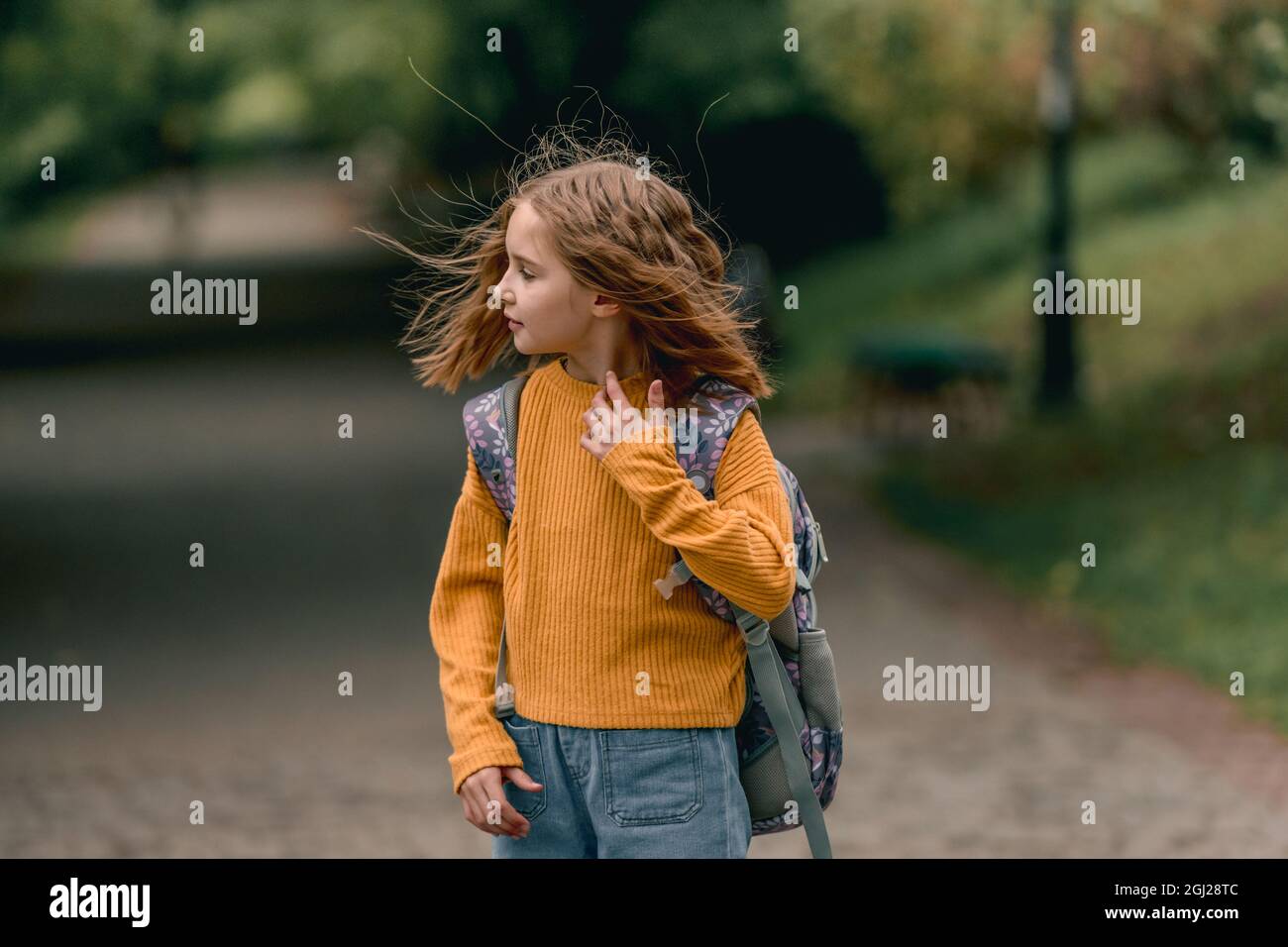 Beautiful girl child with back pack after school looking back at the ...