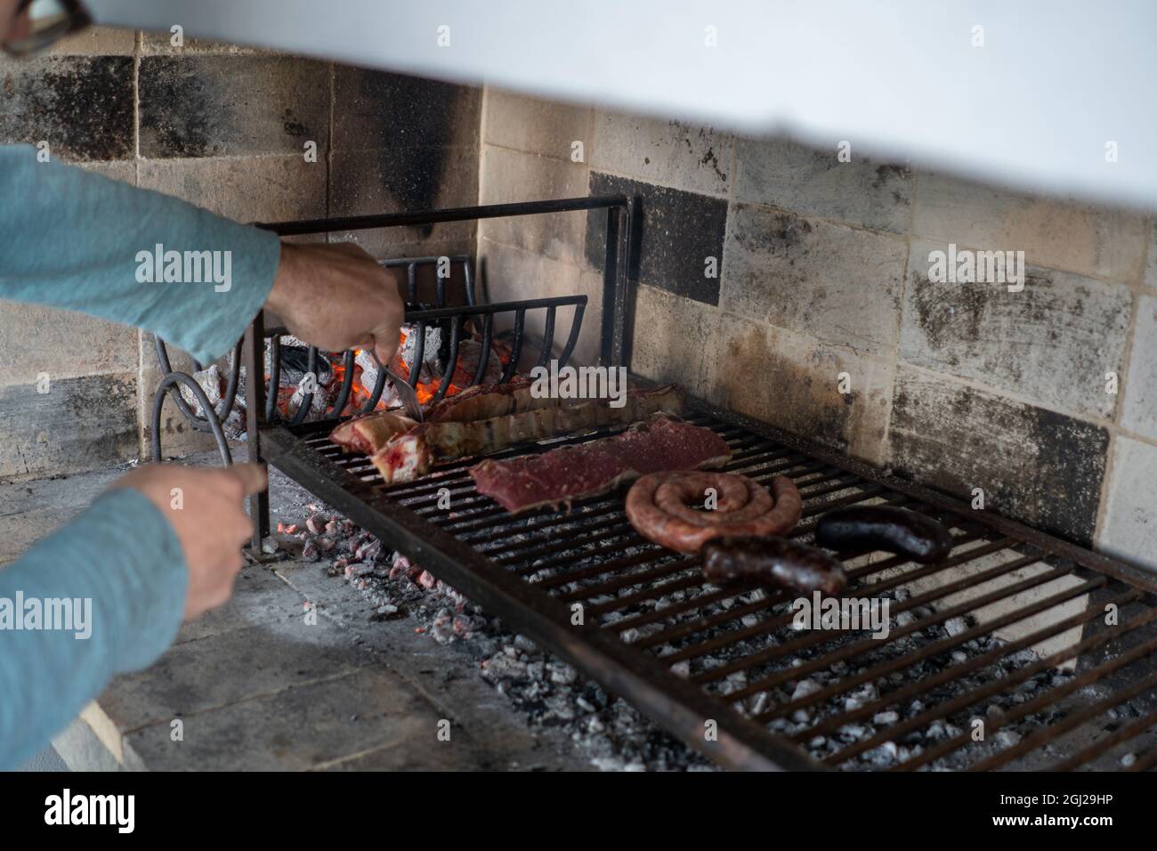 Cook preparing a typical Argentinian Asado with beef and sausage Stock ...