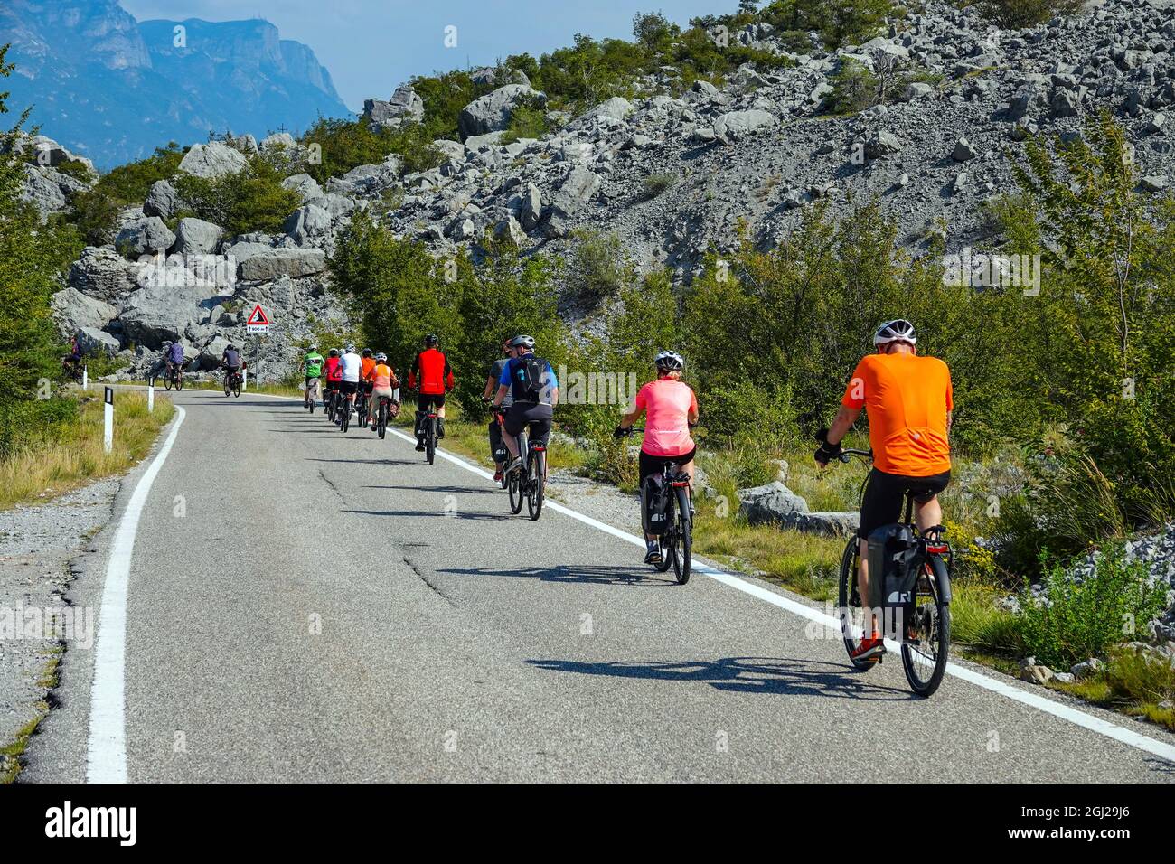 A line of colourful cyclists at the ancient rockfall of the Biotopo ...