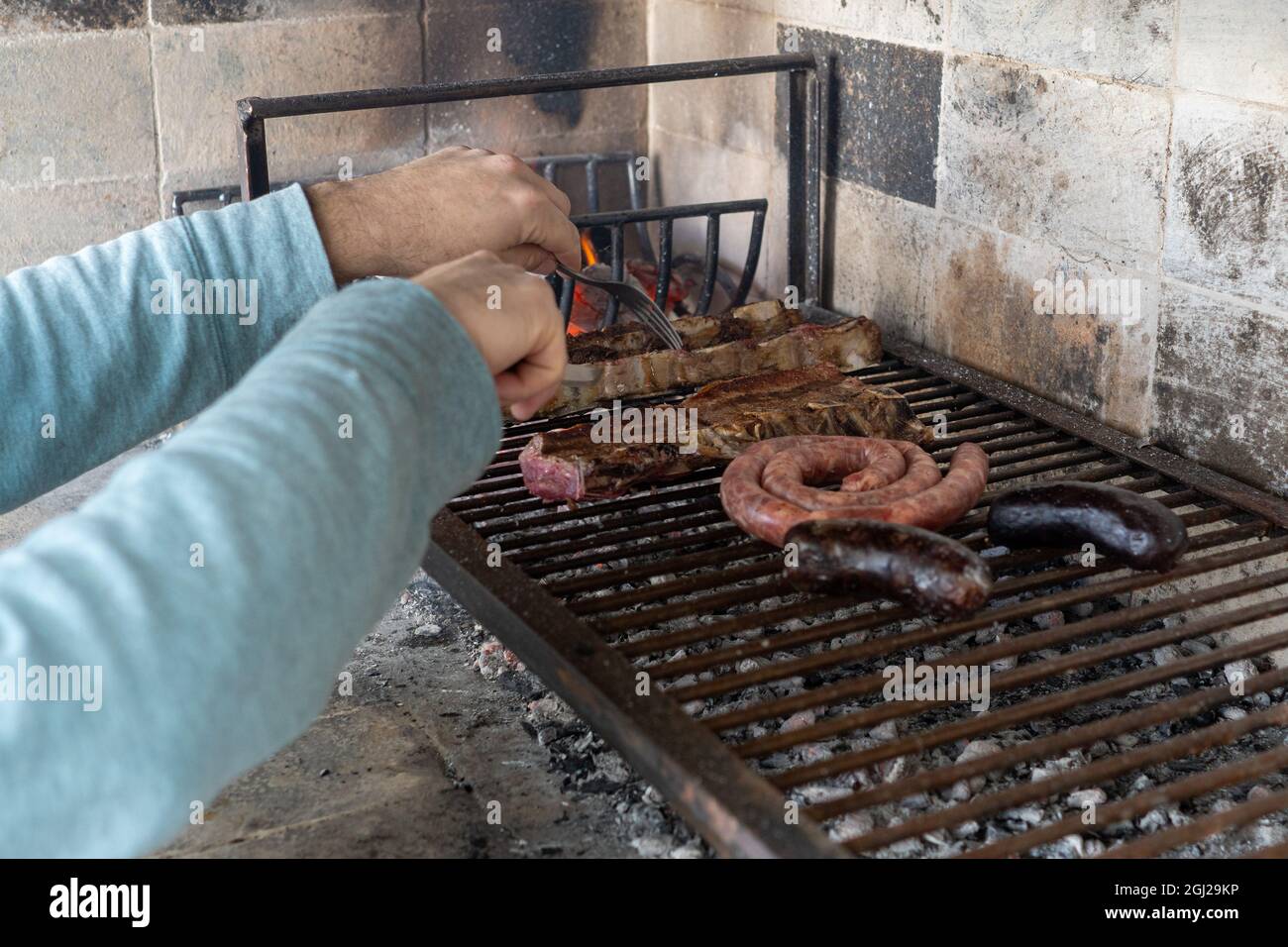 Cook preparing a typical Argentinian Asado with beef and sausage Stock ...