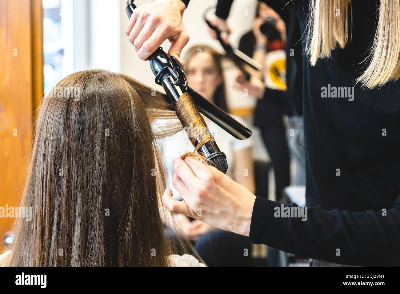 Master woman hairdresser gently curls hair curling girl in a beauty ...