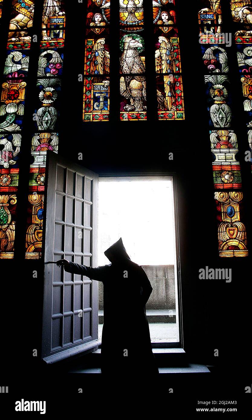 Benedictine monk opening a door under a stained glass window Stock ...