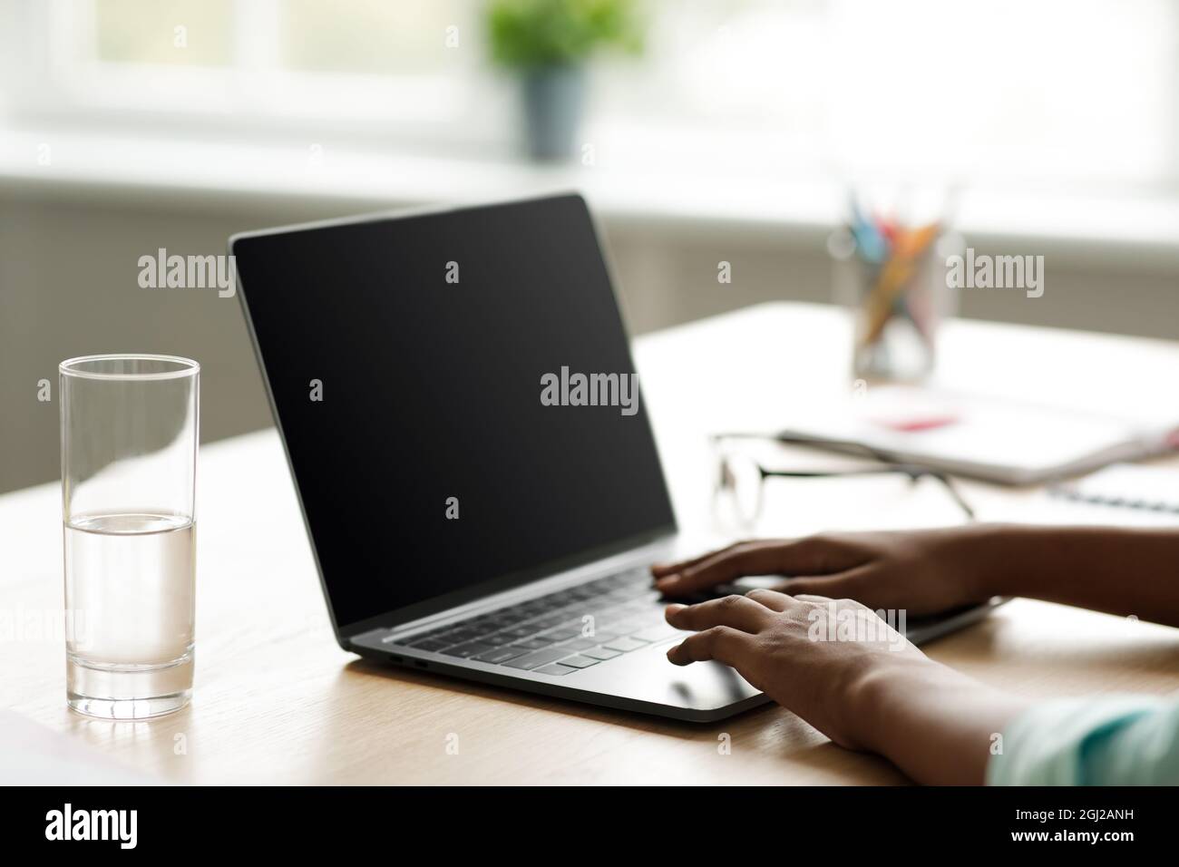 Teenage african american school girl typing on laptop with mockup blank ...