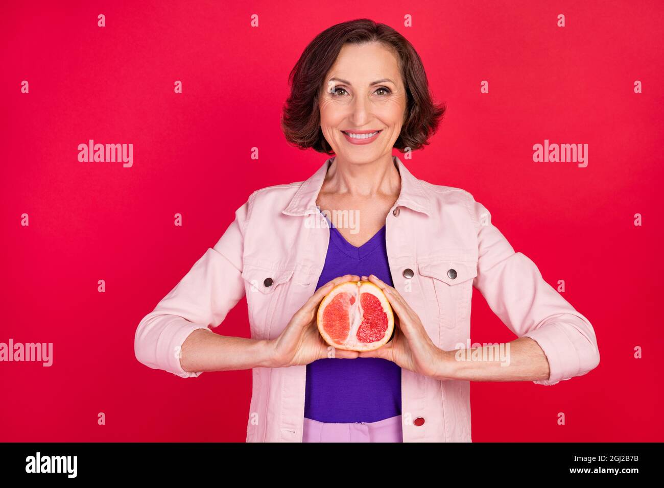 Photo of healthy old lady presenting natural grapefruit slice eye wear ...