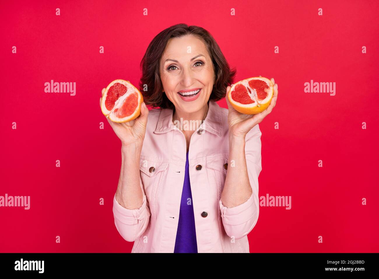 Photo of retired mature lady hold two grapefruit slice beaming smile ...