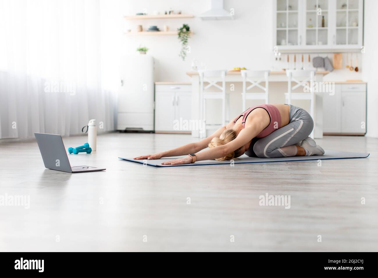 European millennial blonde sportswoman doing body stretching and ...