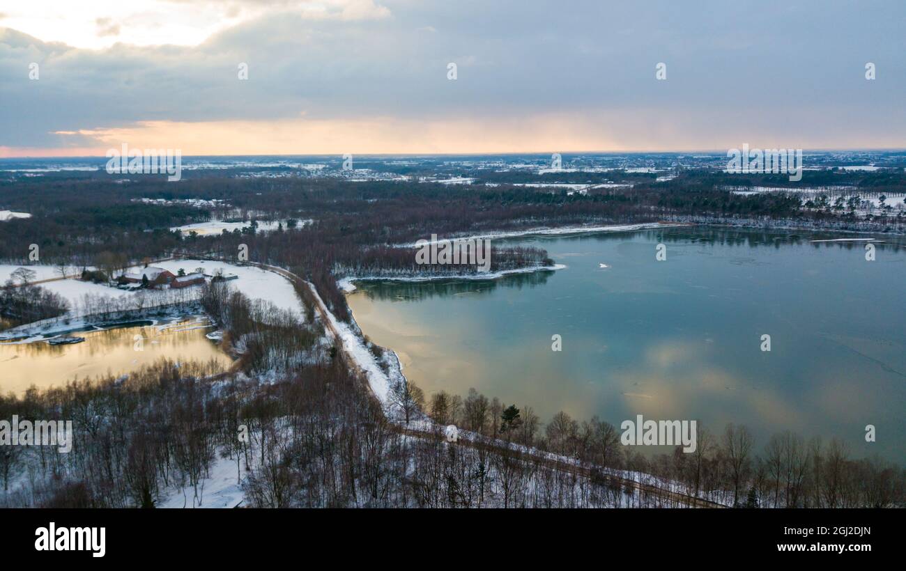 Aerial view of the winter snow covered forest and frozen lake from ...