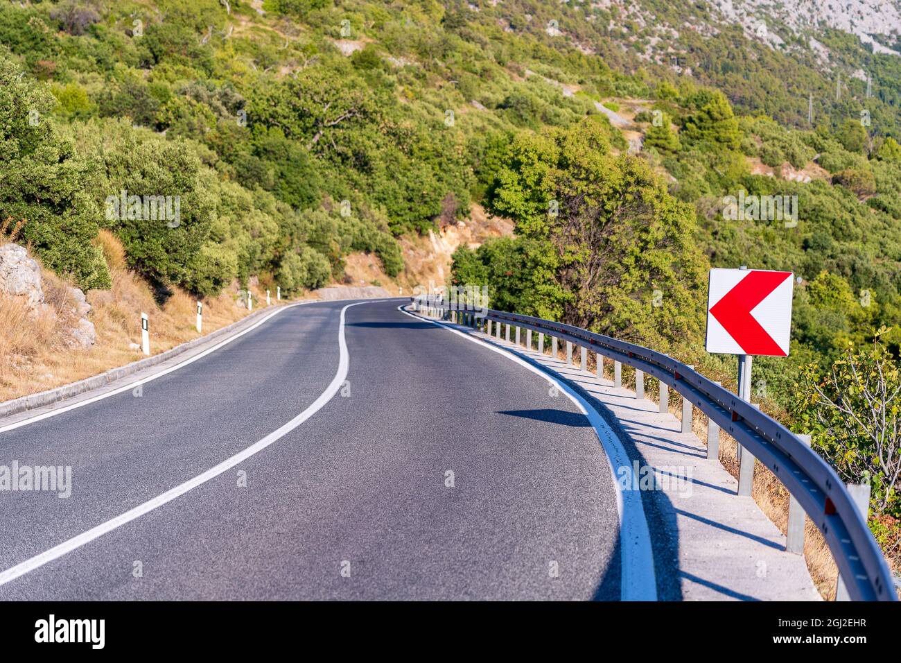 Bend road warning sign on the mountain road in summer time, Europe ...