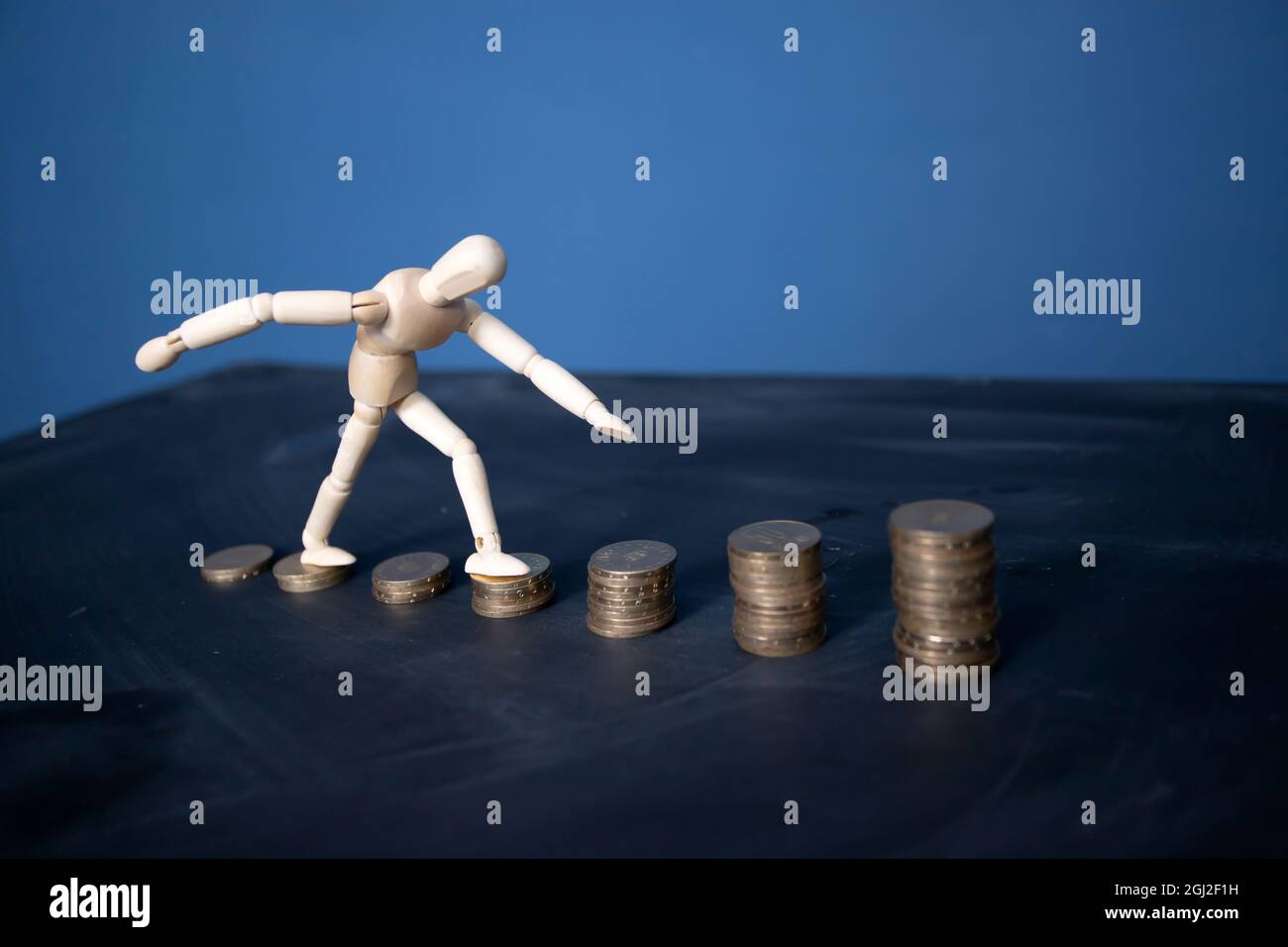 Wooden man wakling on increasing stacks of coins. Concept of hard work ...