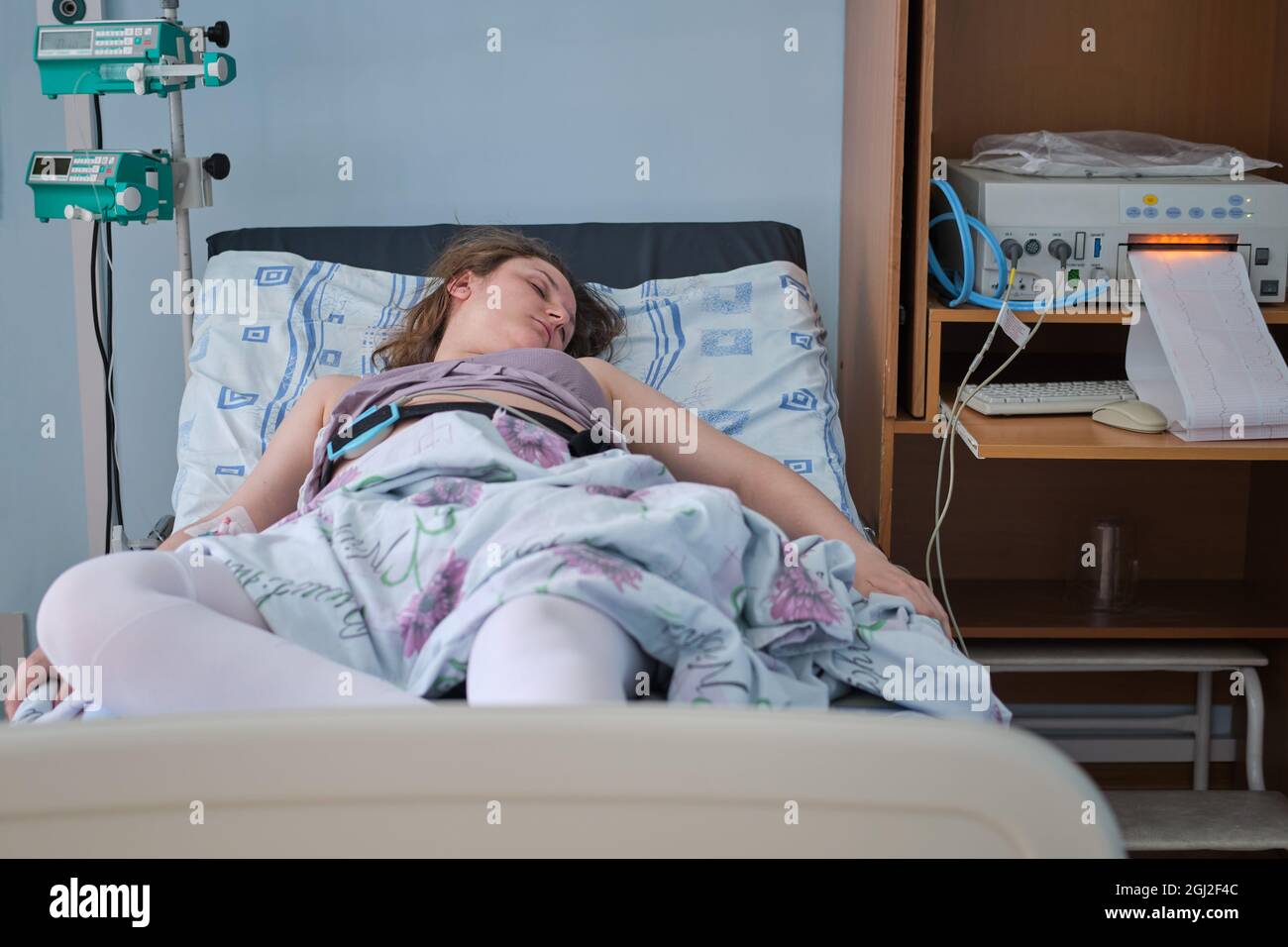 A pregnant woman gives birth in a hospital with a drip and a CTG ...
