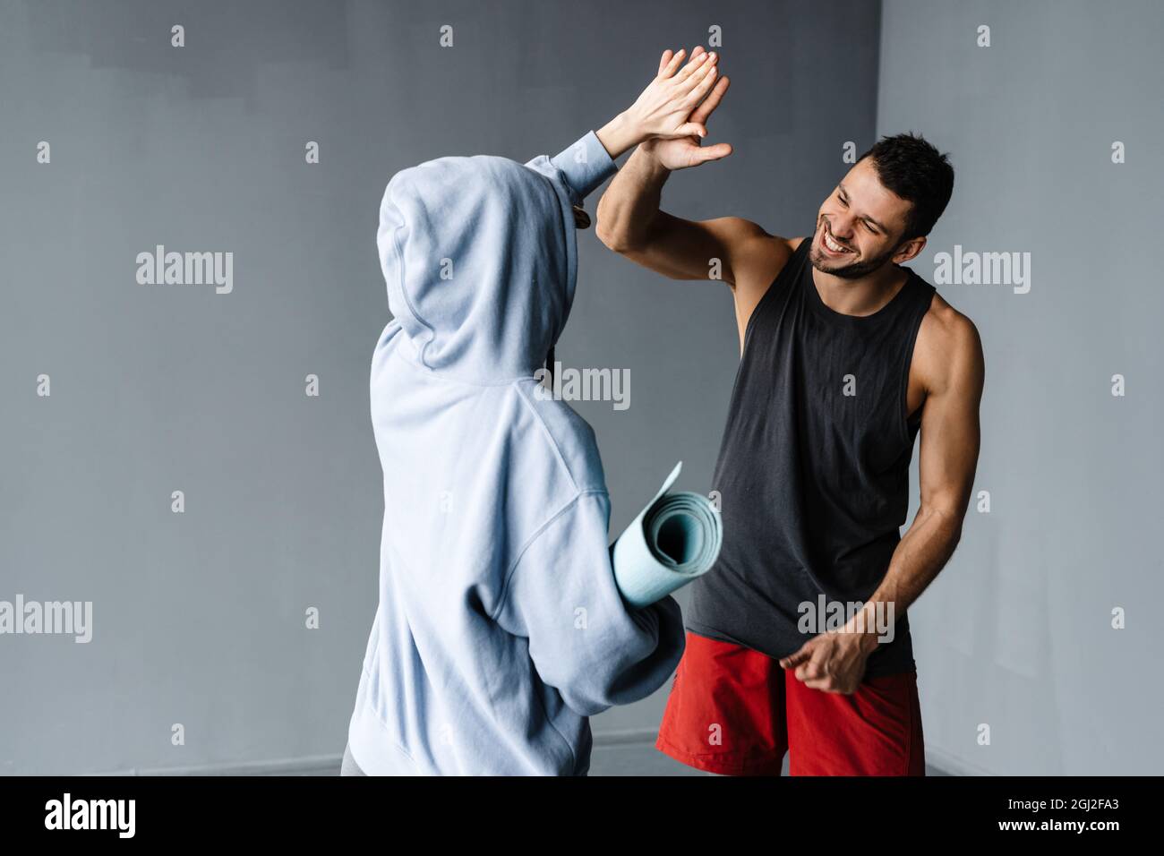 Young fitness coach and his student giving high five during class ...