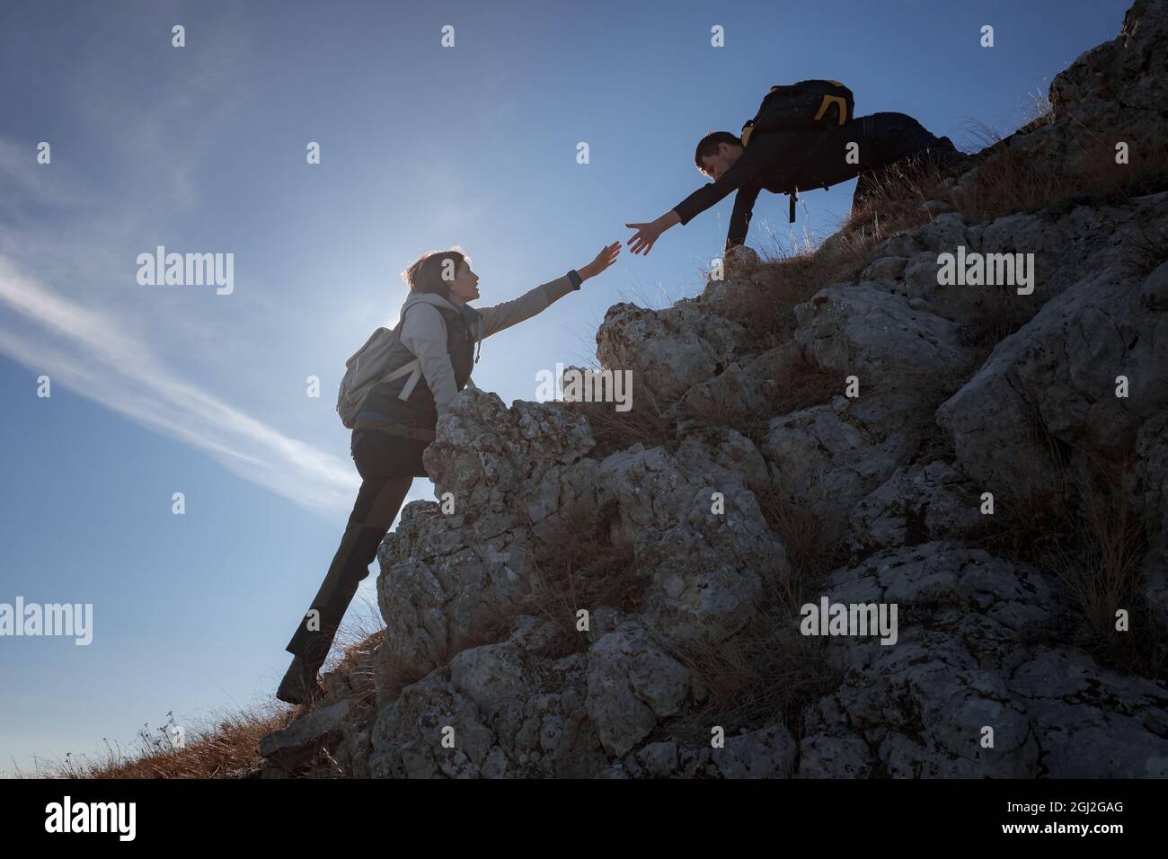 Help and assistance concept. Silhouettes of two people climbing ...