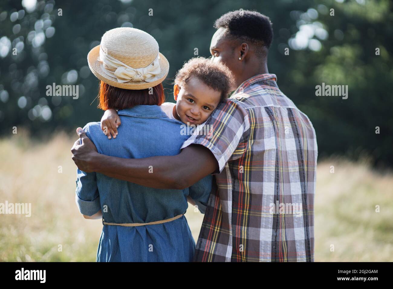 Cute african boy smiling and looking at camera while sitting on hands ...