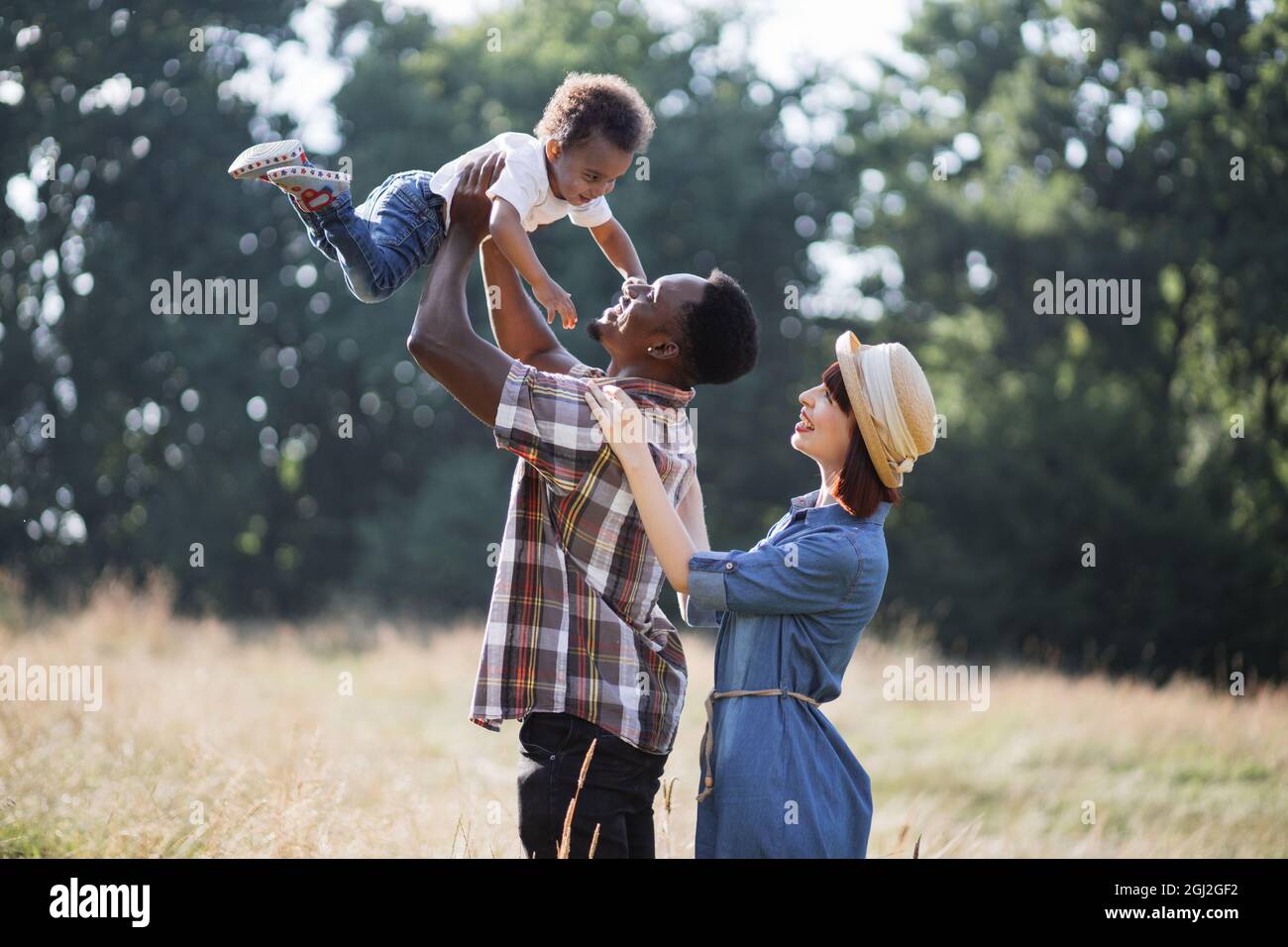 Side view of african american father throwing little son up in air ...