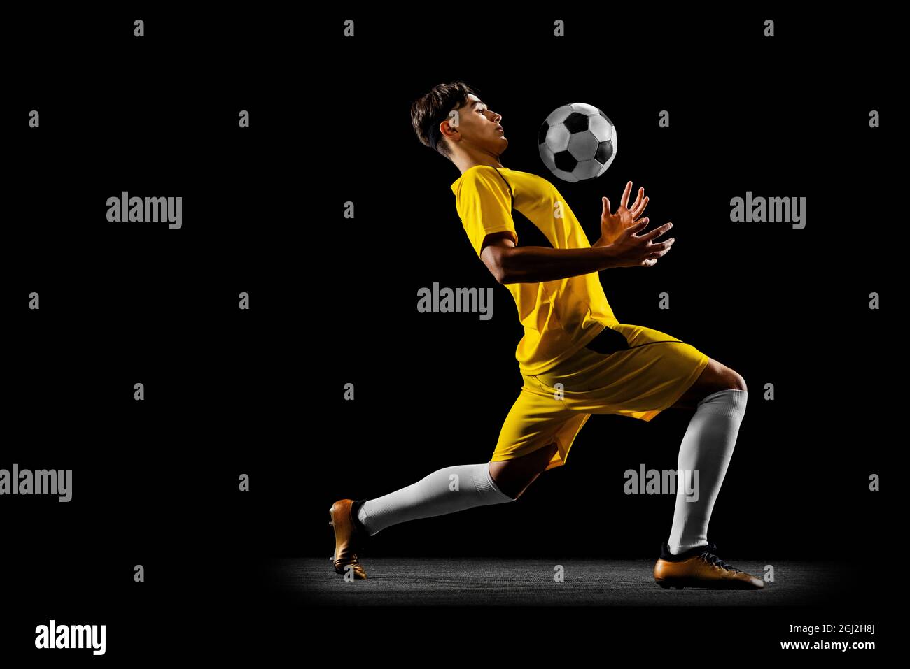 Young male football player training isolated on black background Stock Photo - Alamy
