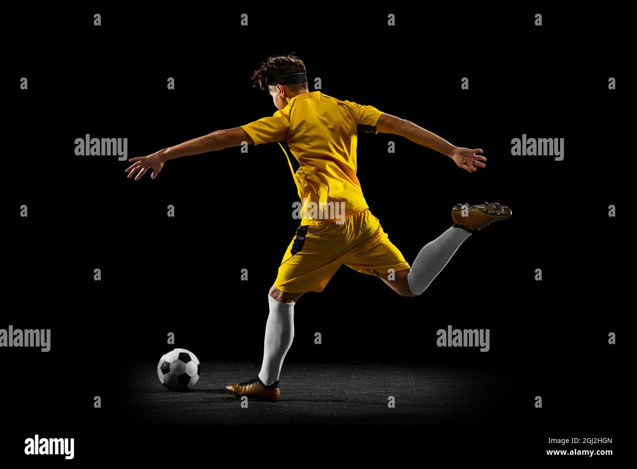 Full-length back view portrait of young man, football player training ...