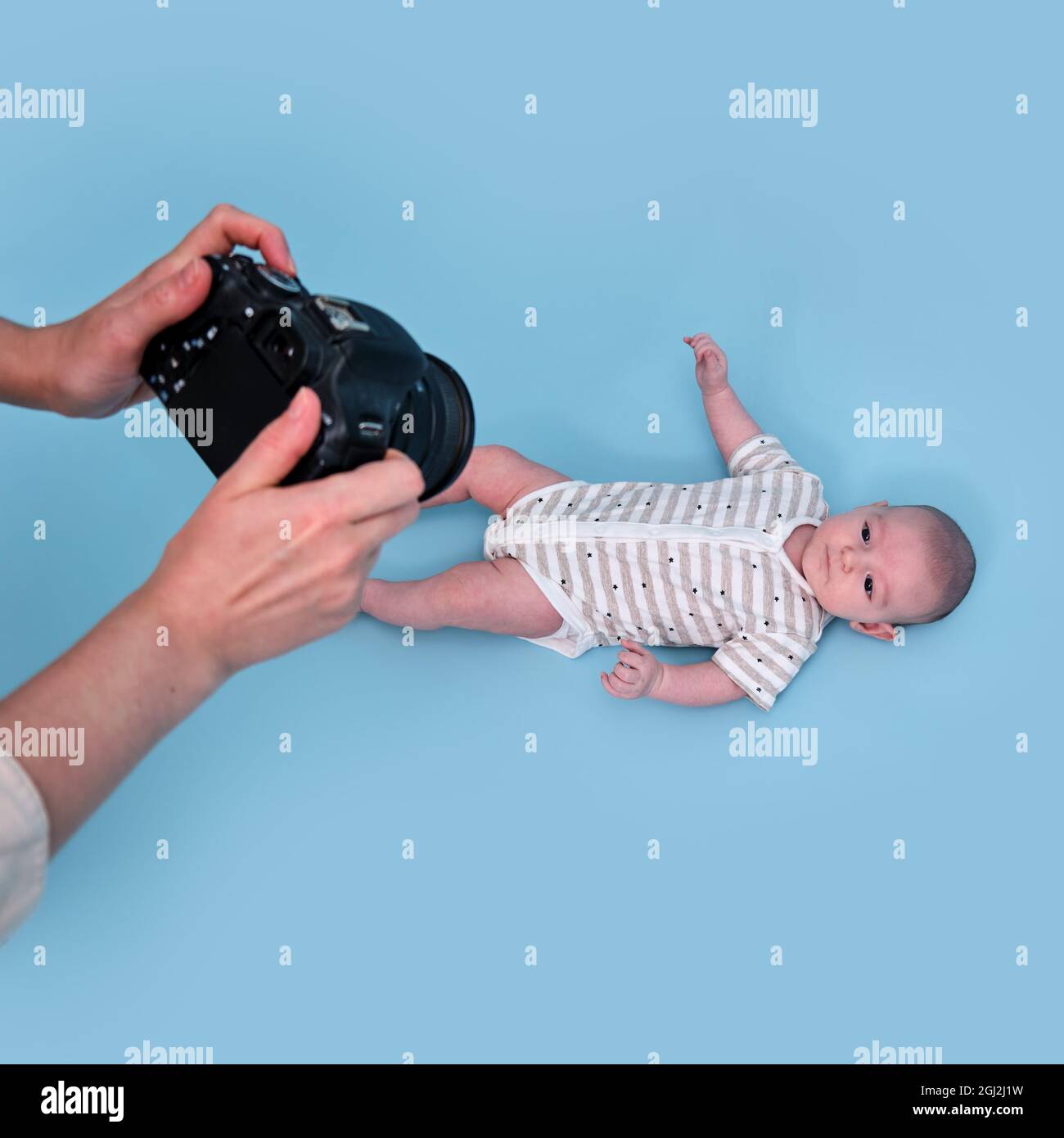 A photographer takes pictures of a newborn baby with a camera on a blue ...