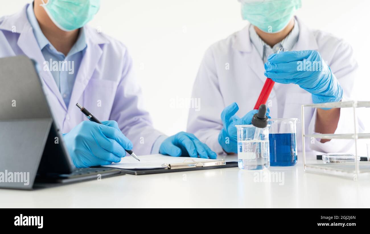 Attractive young scientist team in lab coat and safety goggles working ...