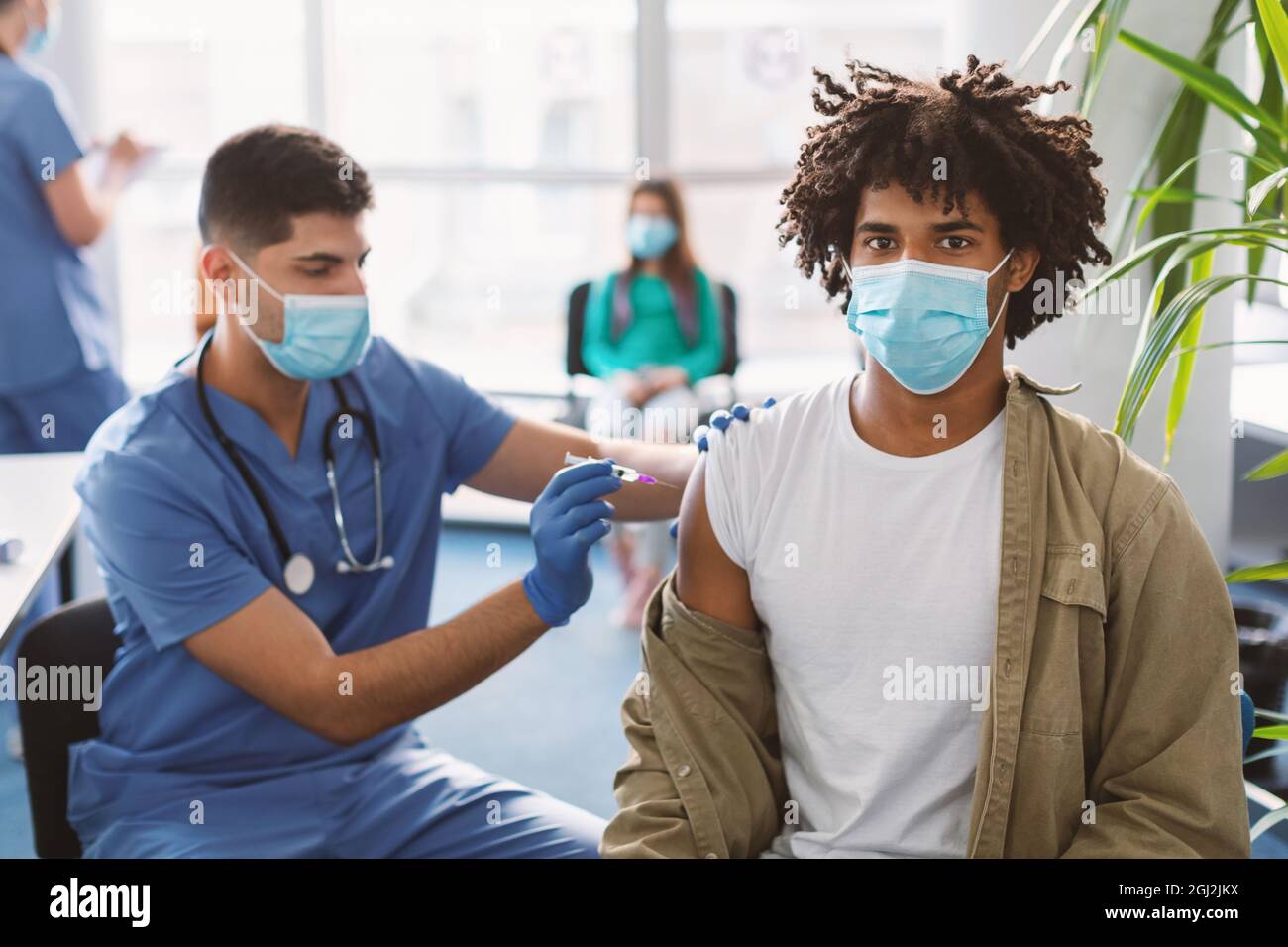 Male doctor or nurse giving shot or vaccine to a patient's shoulder ...