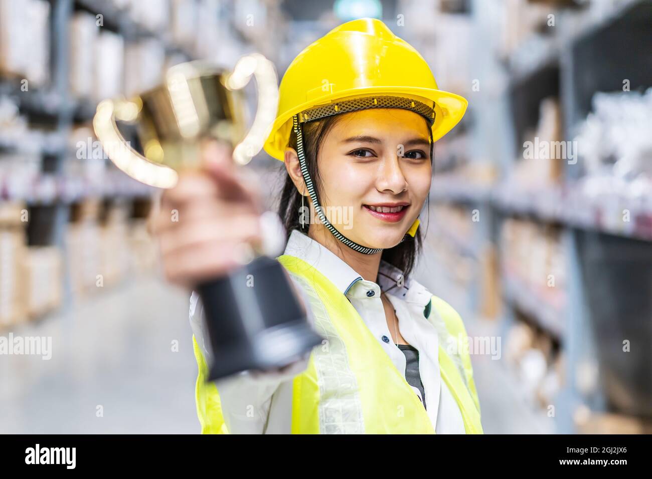Happy woman warehouse worker holding a trophy after being selected as ...