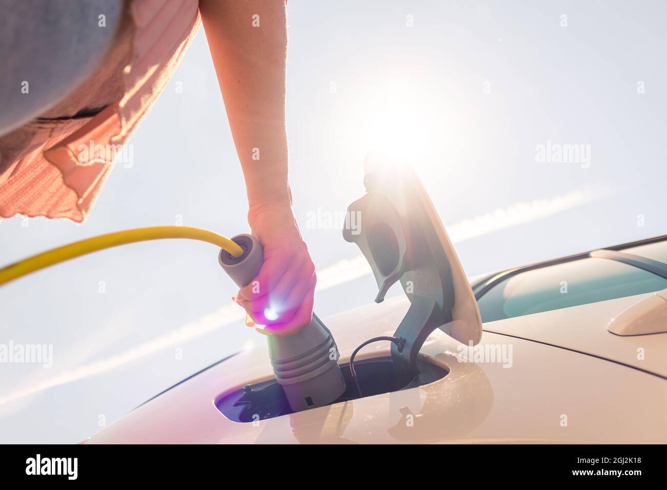 Female hands opening an electric car charging socket cap and plugging ...