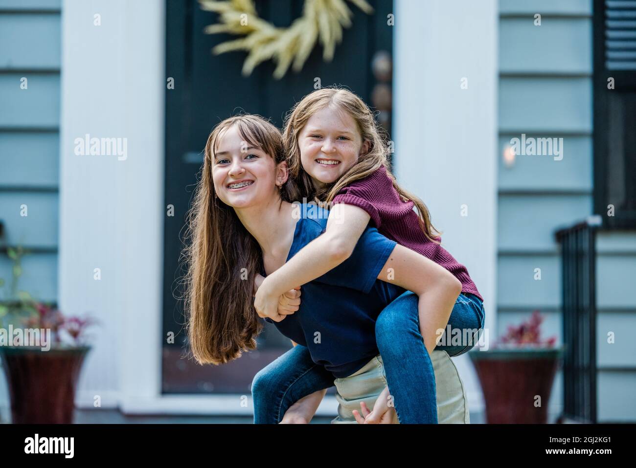 A father holding his 10 year old daughter piggyback on his back while ...