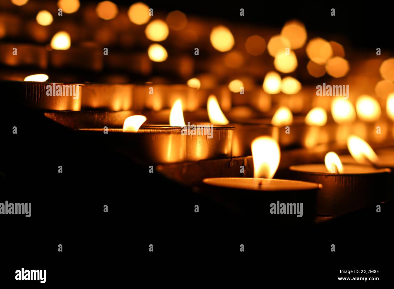 Rows of glowing candles in the dark with bokeh lights Stock Photo - Alamy