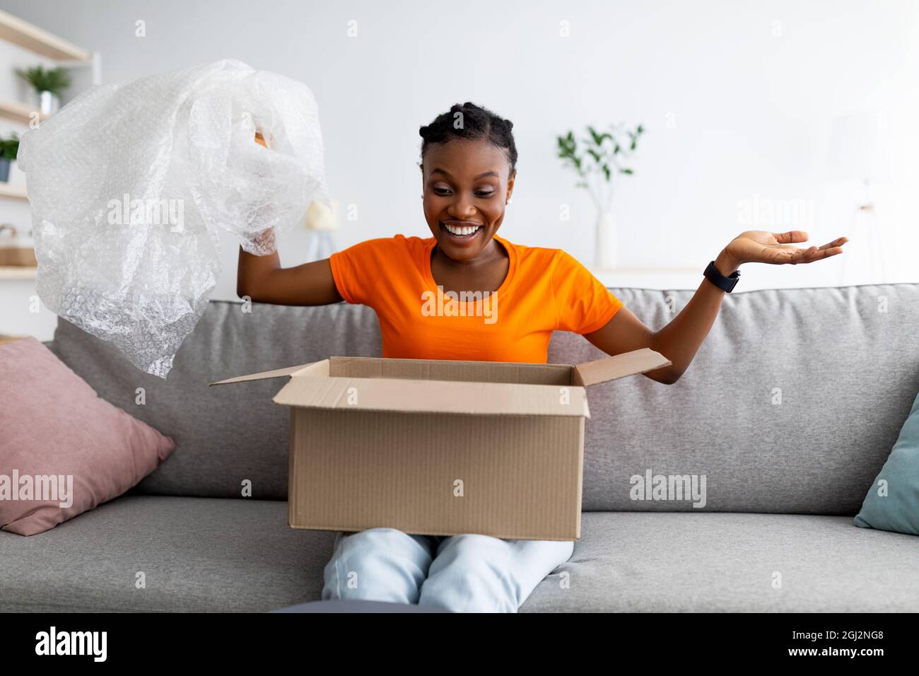 Satisfied buyer. Excited black lady receiving package, unboxing ...
