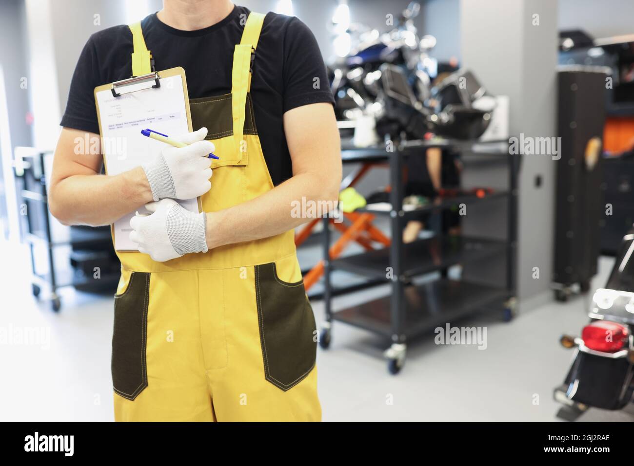Auto mechanic locksmith in yellow uniform stands in car repair shop ...