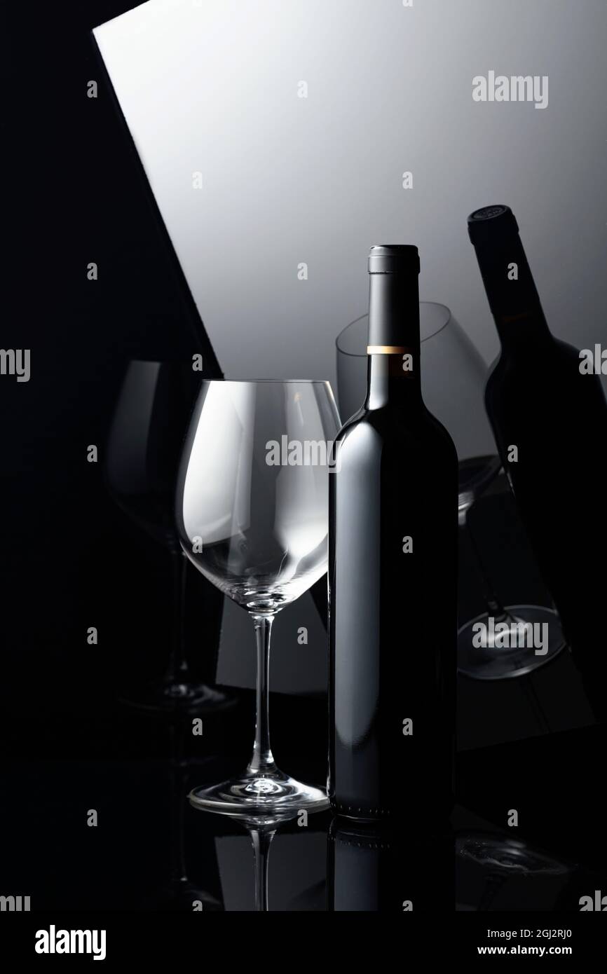 An unopened bottle of red wine with a reflection on the glossy black ...