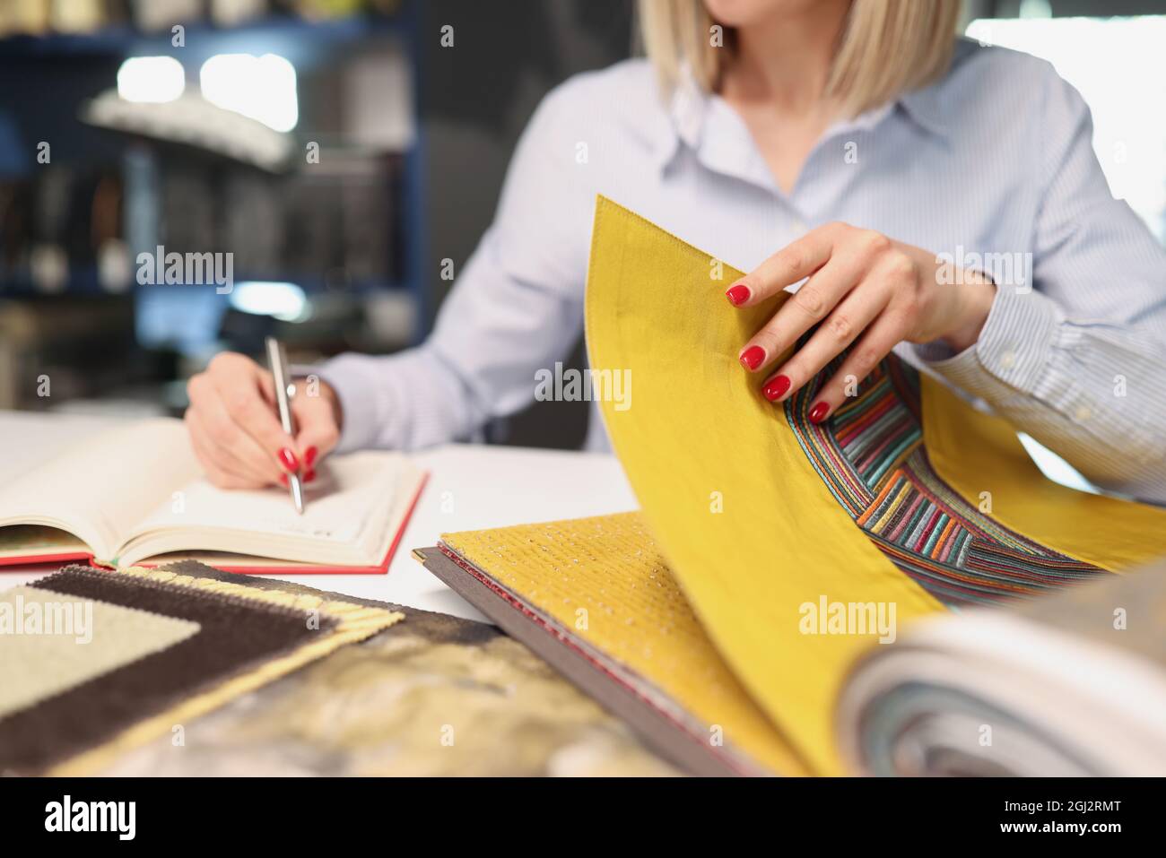 Woman chooses fabric with pattern for upholstery in interior of store ...