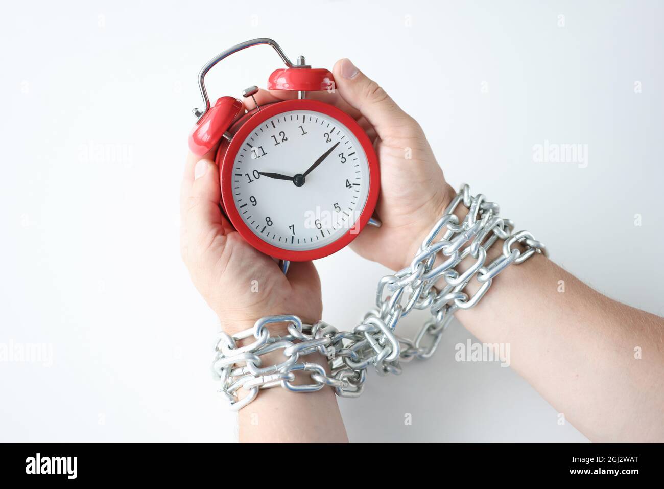 Male hands holding red alarm clock with hands tied by chain closeup ...