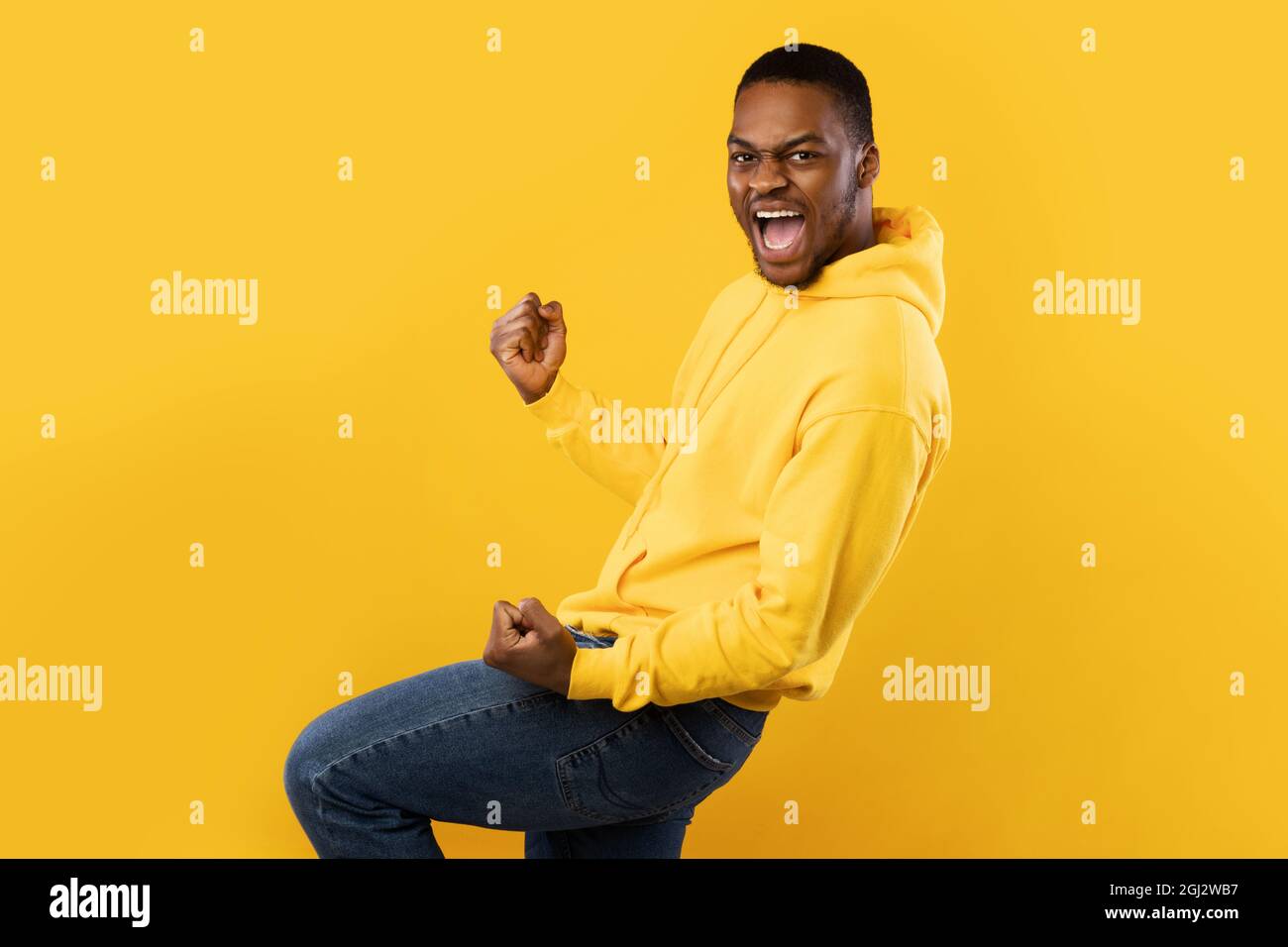 Emotional Black Man Shaking Fists In Joy Posing Over Yellow Background ...