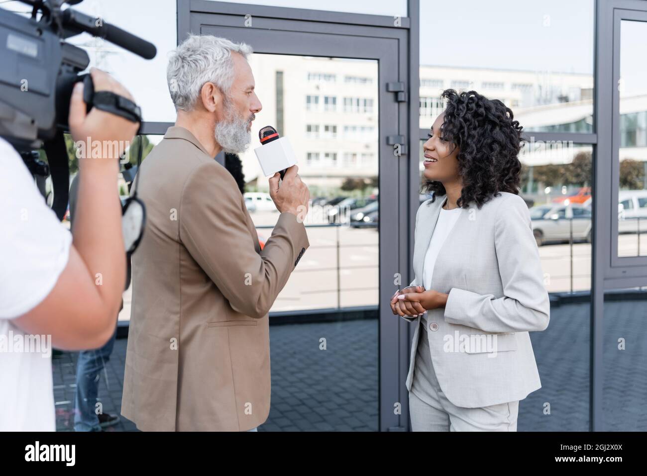 journalist with microphone interviewing smiling african american ...