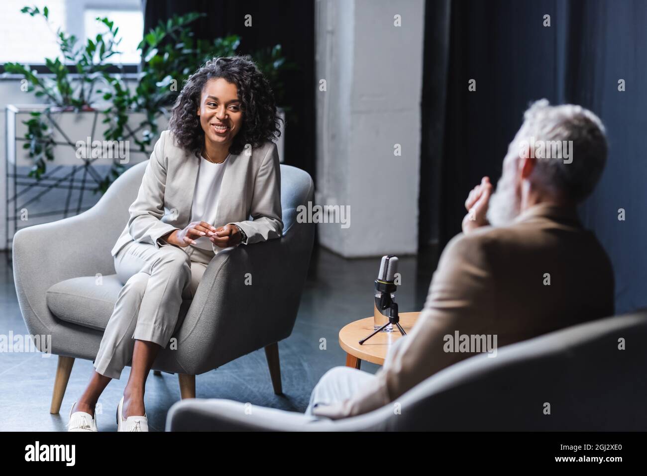 happy african american journalist gesturing while talking with blurred ...