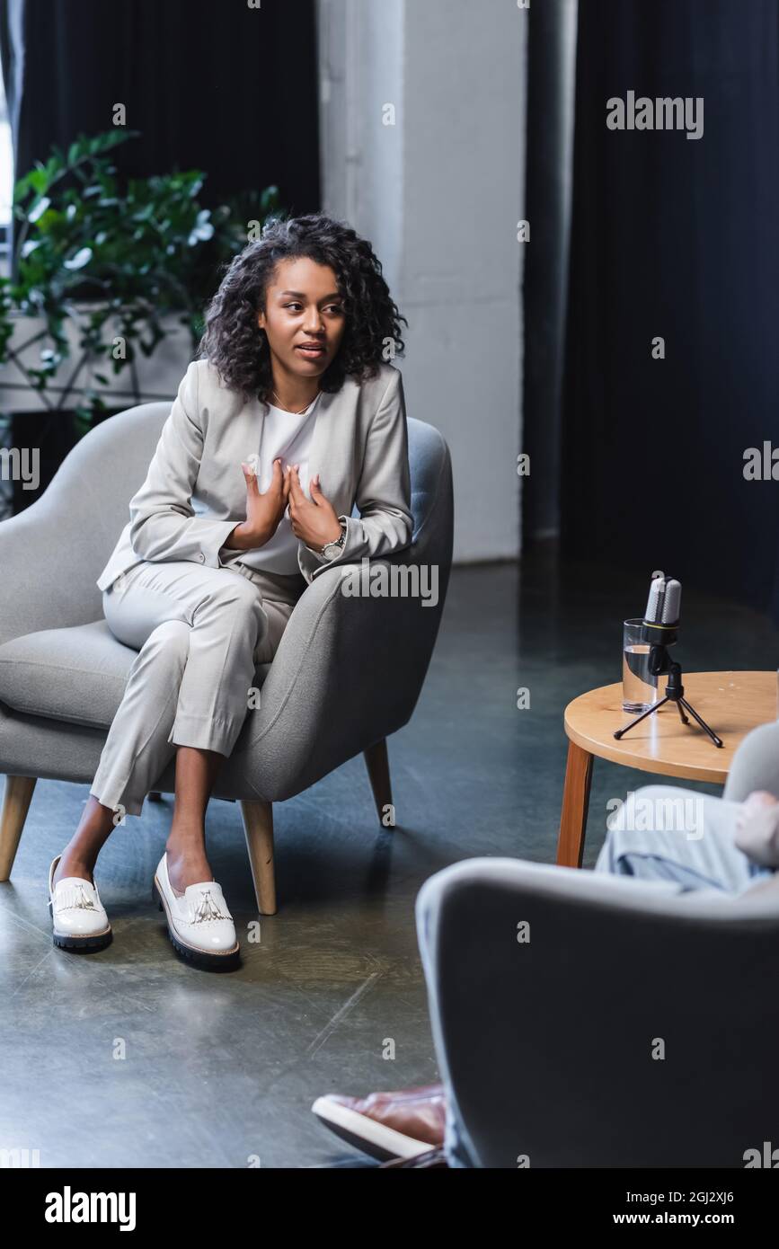 african american journalist gesturing while talking with blurred guest ...