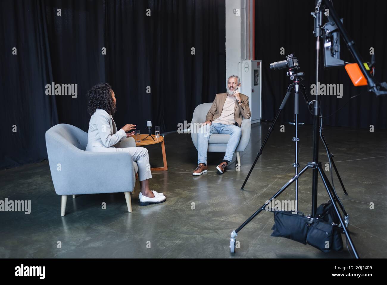 african american journalist talking with smiling businessman sitting in ...