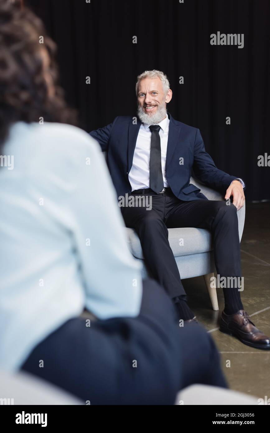 cheerful businessman in suit looking at blurred african american ...