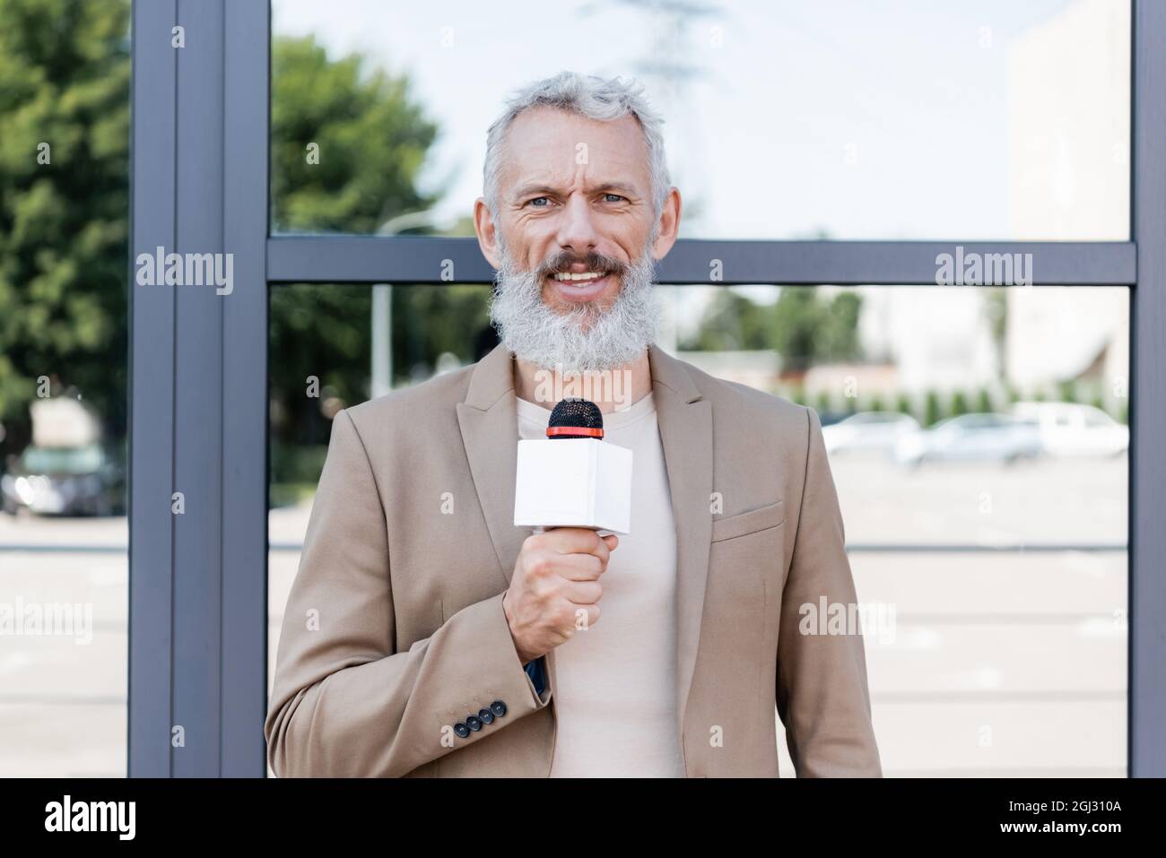 bearded announcer in blazer holding microphone and making reportage ...