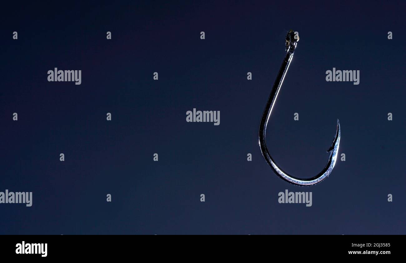 Closeup of a fishhook isolated on a dark blue background Stock Photo ...