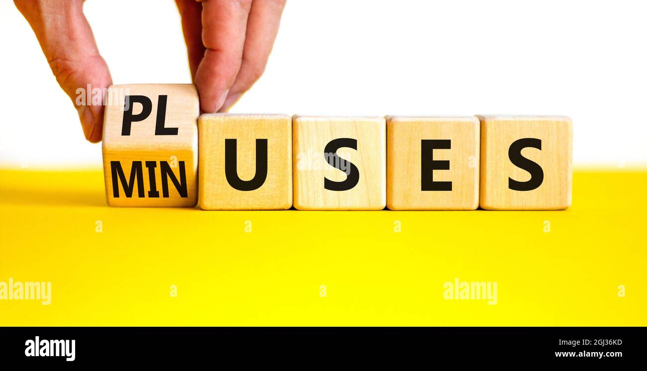 Pluses and minuses symbol. Businessman turns a wooden cube and changes ...