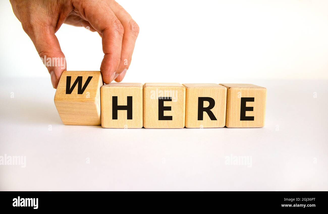Where or here symbol. Businessman turns a wooden cube, changes the word ...