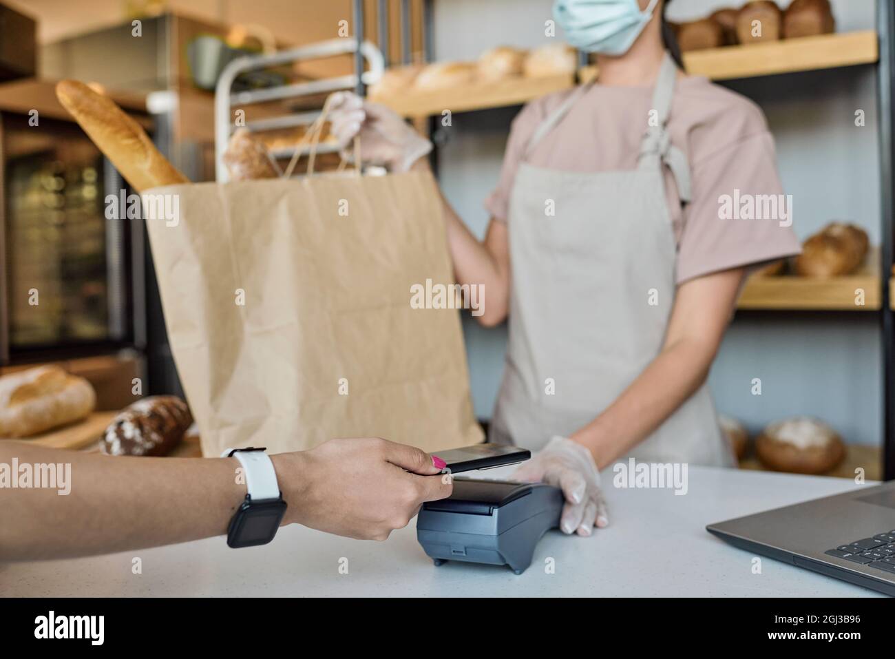 Close-up of unrecognizable female clerk of bakery in gloves giving ...