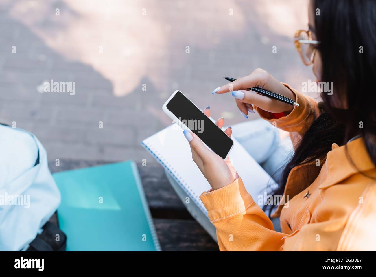 partial view of asian student using mobile phone with blank screen ...