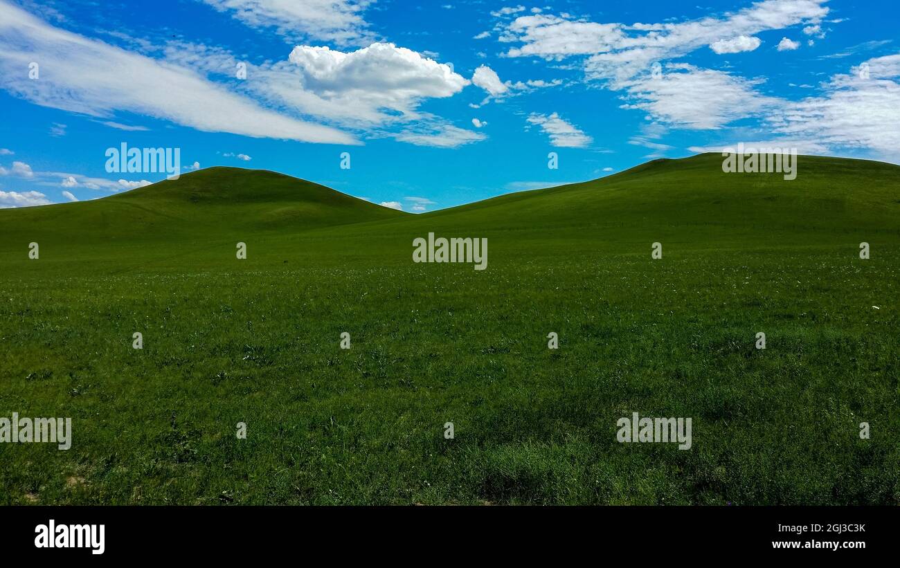 Beautiful view of two small green hills with a blue sky background ...