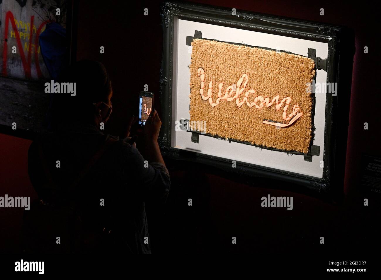 A guest uses a cell phone to photograph displayed works by artist ...